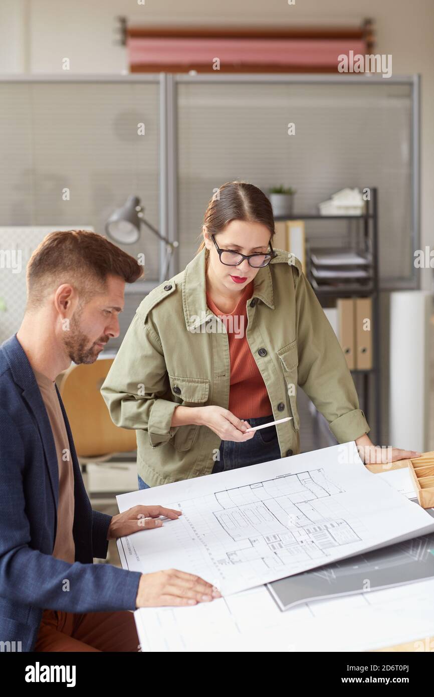 Vertical portrait of two architects looking at blueprints and ...