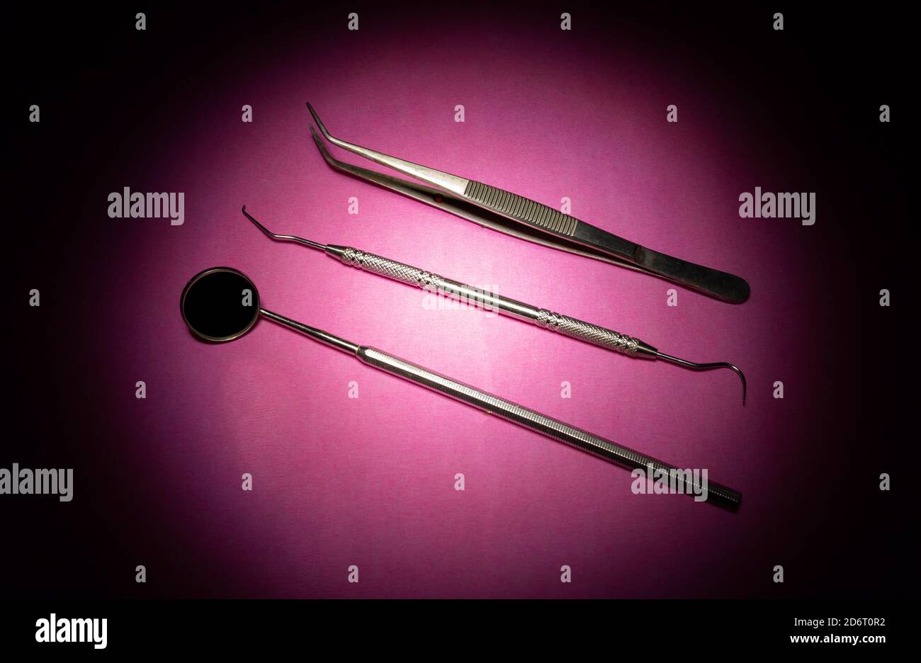 From above of various dental instruments arranged in row on pink table ...