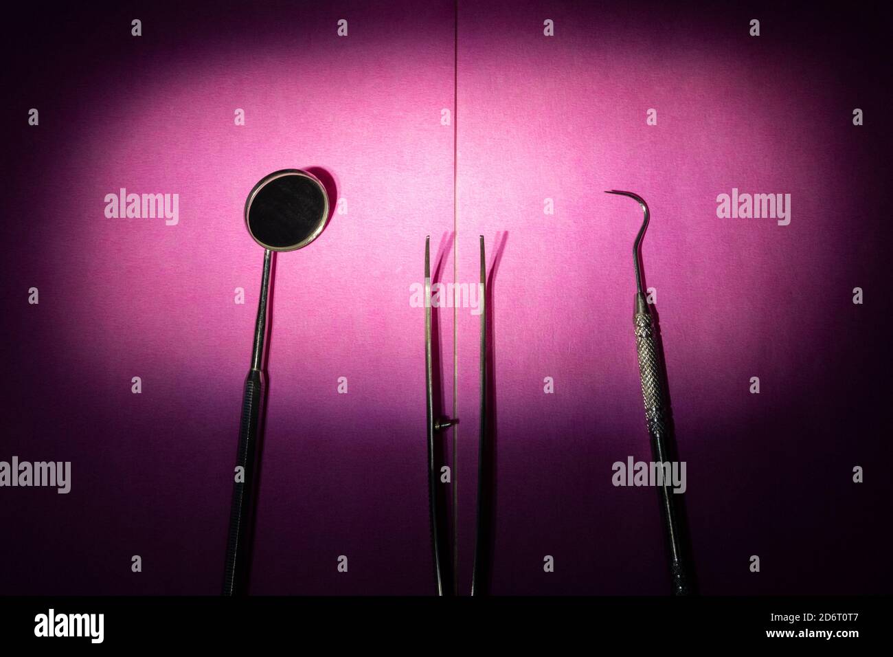 From above of various dental instruments arranged in row on pink table ...