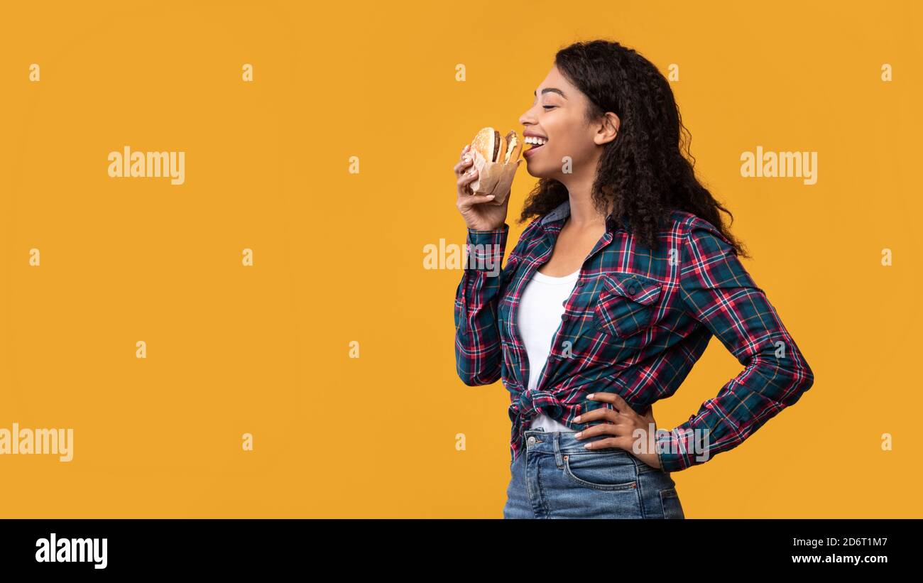 Funny African American Lady Eating Burger At Orange Studio Stock Photo ...