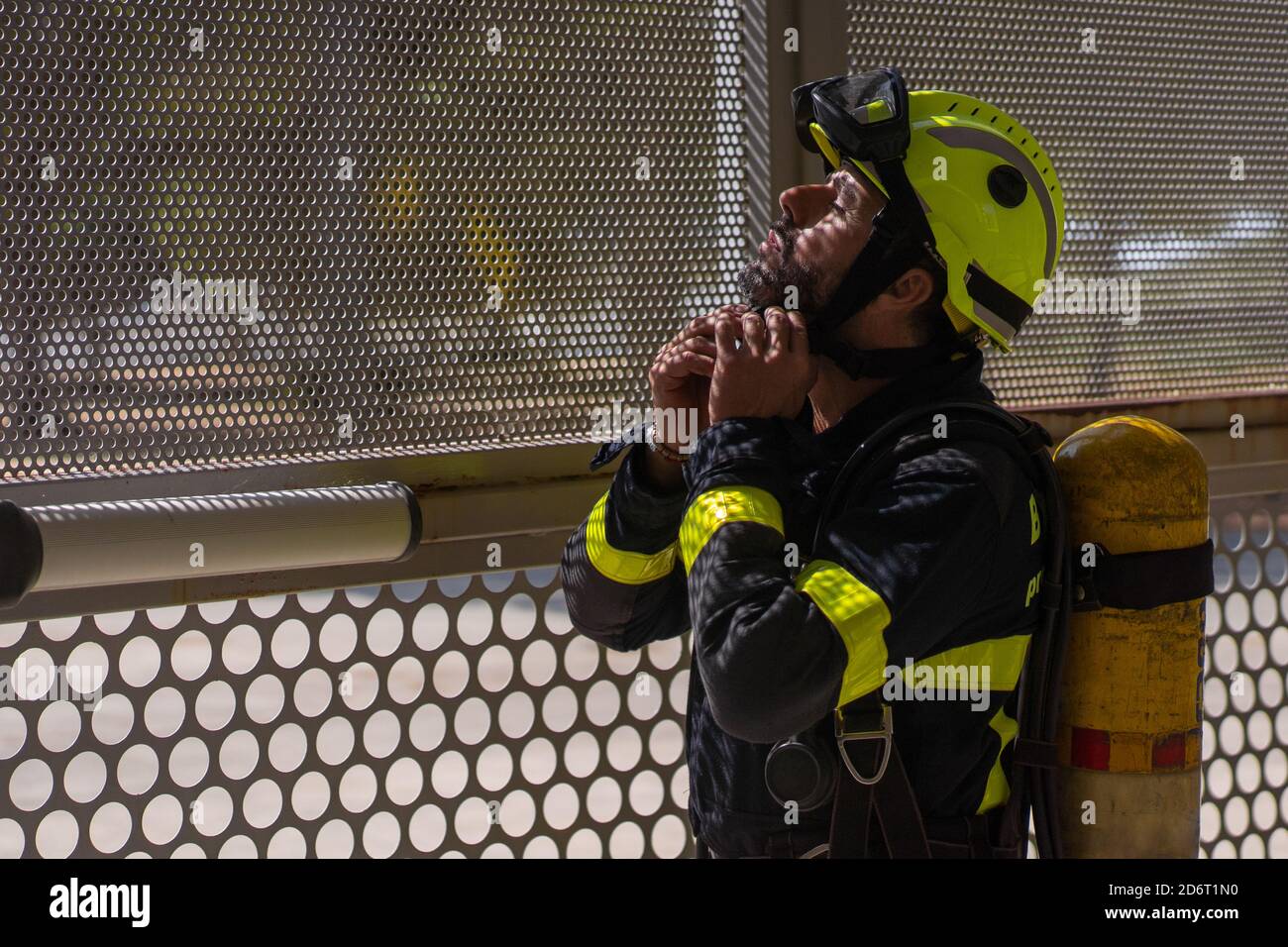 Side view of unshaven firefighter in colorful uniform putting on ...