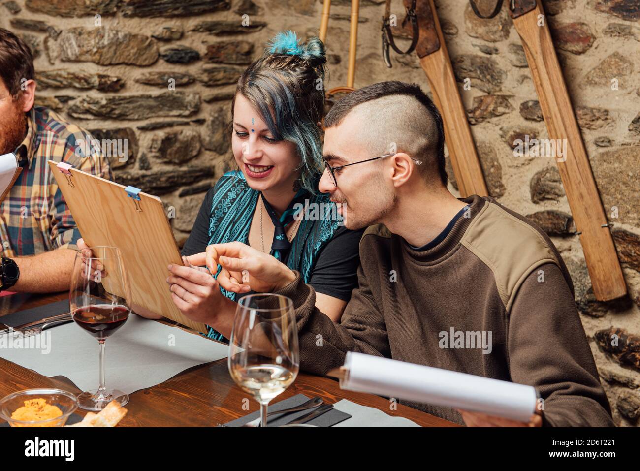 Group of friends gathering at table in restaurant and discussing menu ...