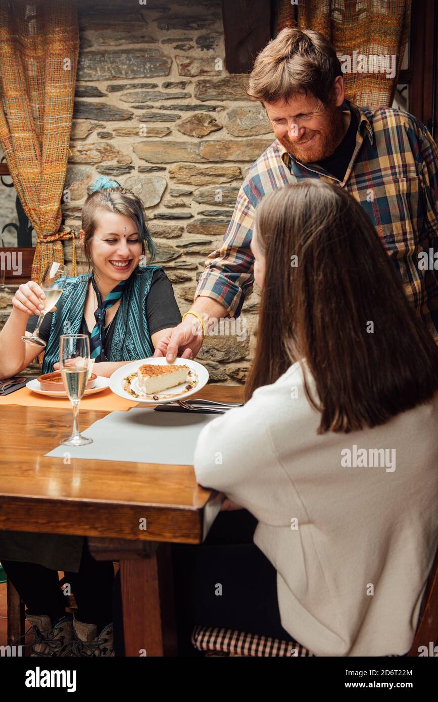 Male standing at wooden table in cafe with group of friends and ...