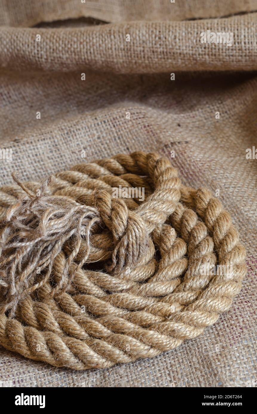 Thick natural rope wound in a reel on sackcloth. Close-up of a laid ...