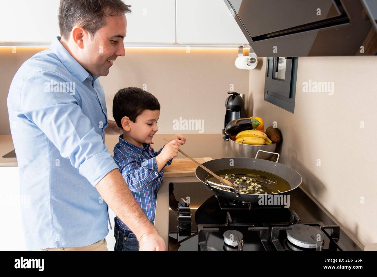 Side view cute concentrated boy stirring garlic on frying pan while ...