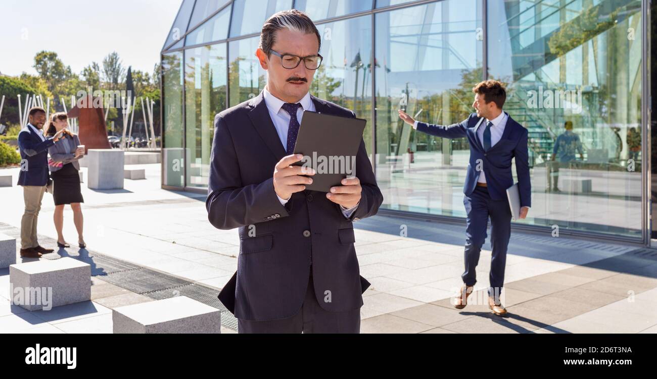 Serious middle aged male manager with mustache in classy outfit holding ...