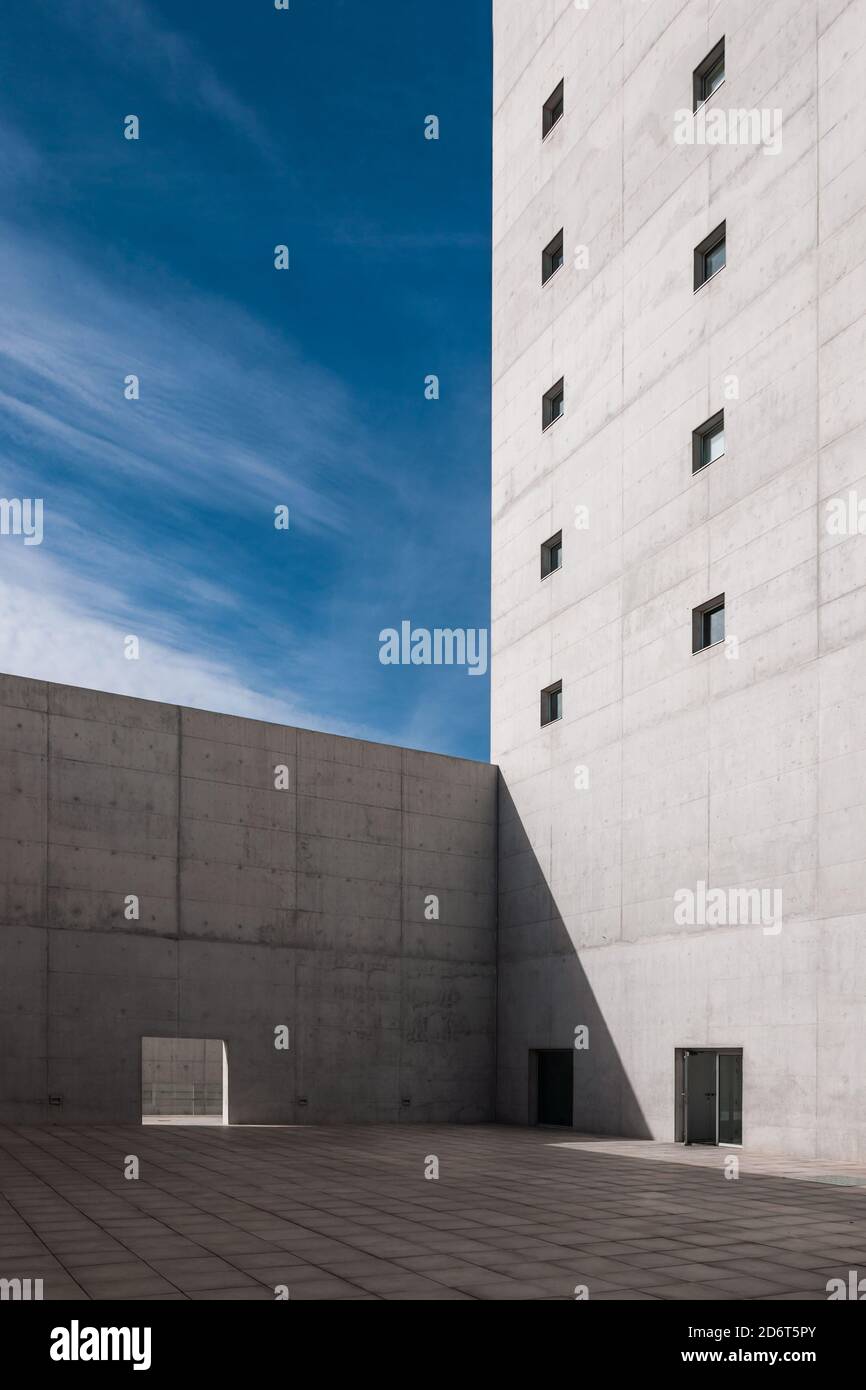 Facade of gray monolithic brutalist building with tiny windows and gate ...