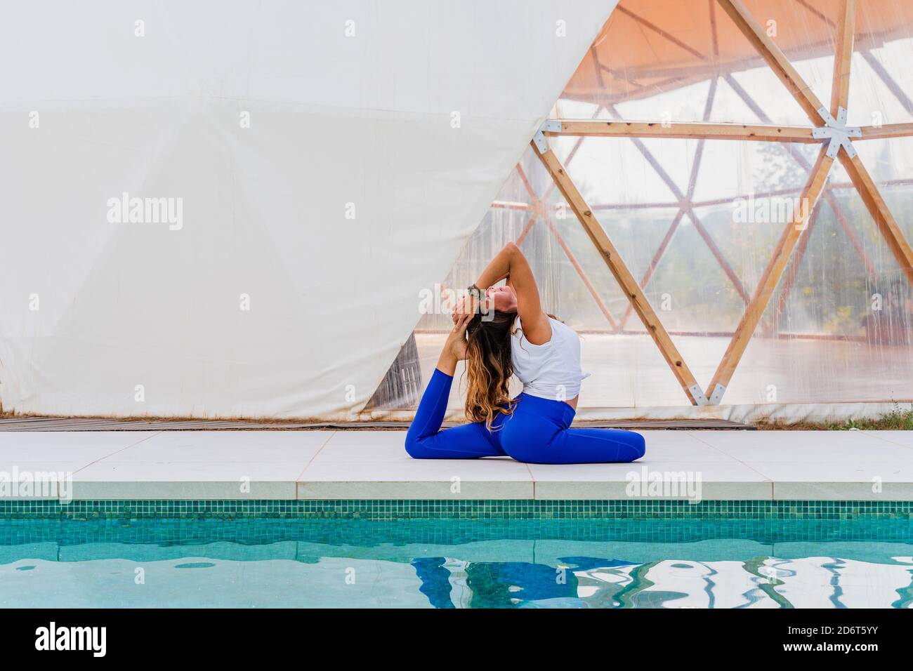 Side view of anonymous barefoot lady sitting in Eka Pada Rajakapotasana ...