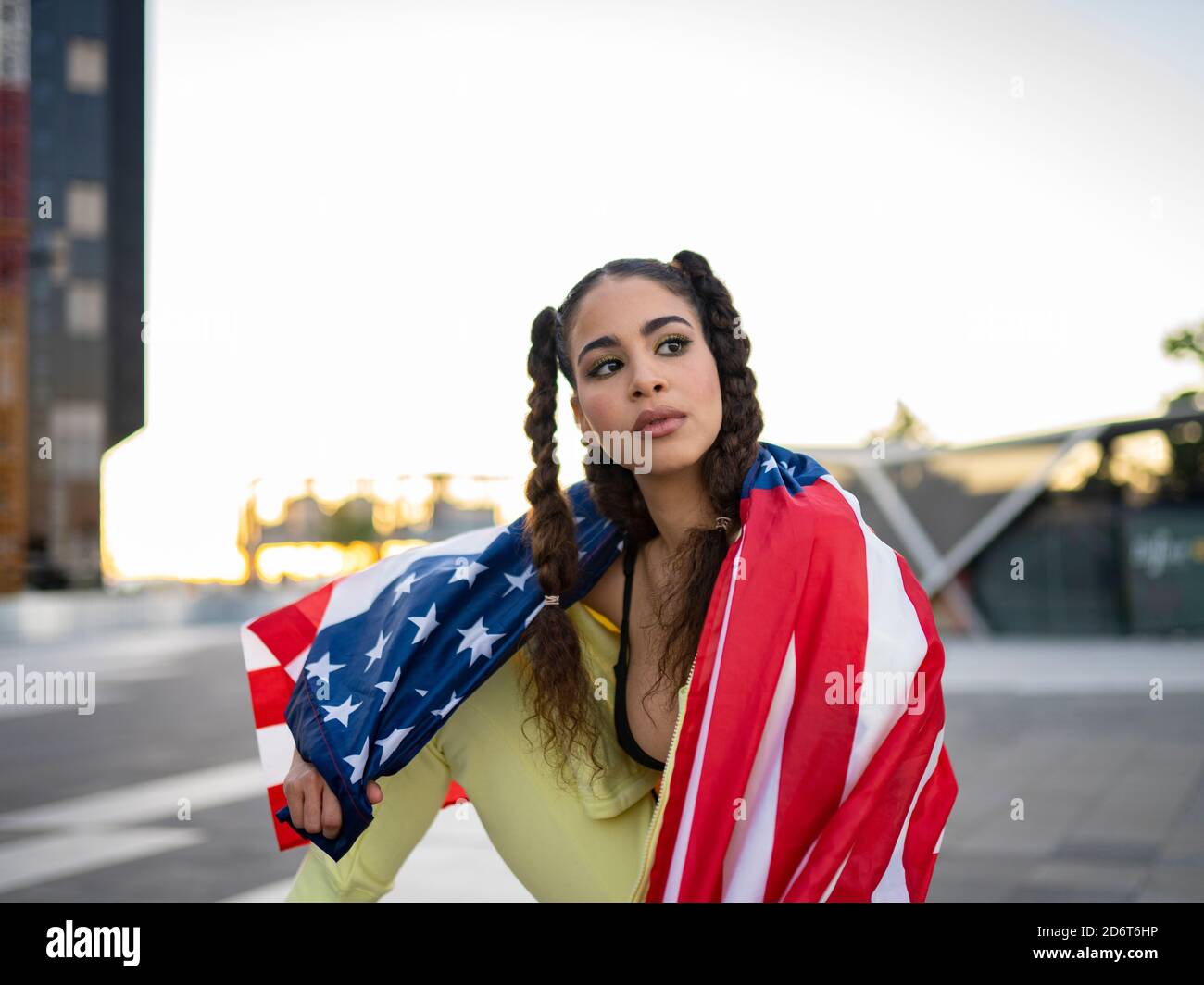 Confident young ethnic lady in sports bra waving American flag and ...
