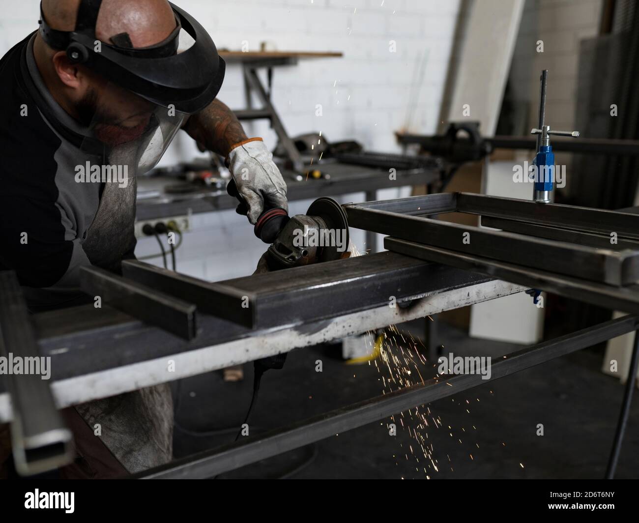Side view of serious male welder using electric grinder and cutting ...