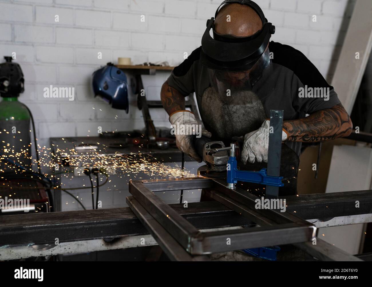 Side view of serious male welder using electric grinder and cutting ...