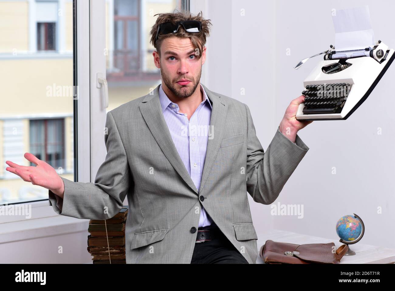 Young author or editor holds old typewriter on window background ...