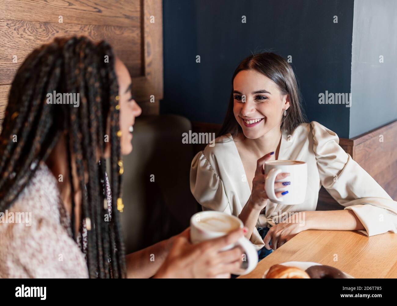 Cheerful young multiracial women in trendy outfits drinking coffee and ...
