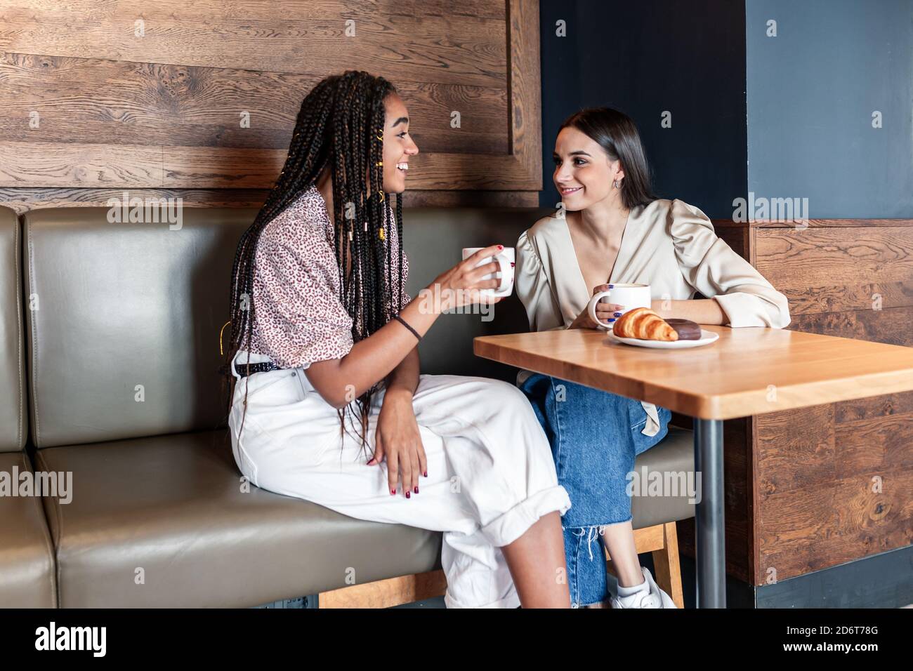 Cheerful young multiracial women in trendy outfits drinking coffee and ...