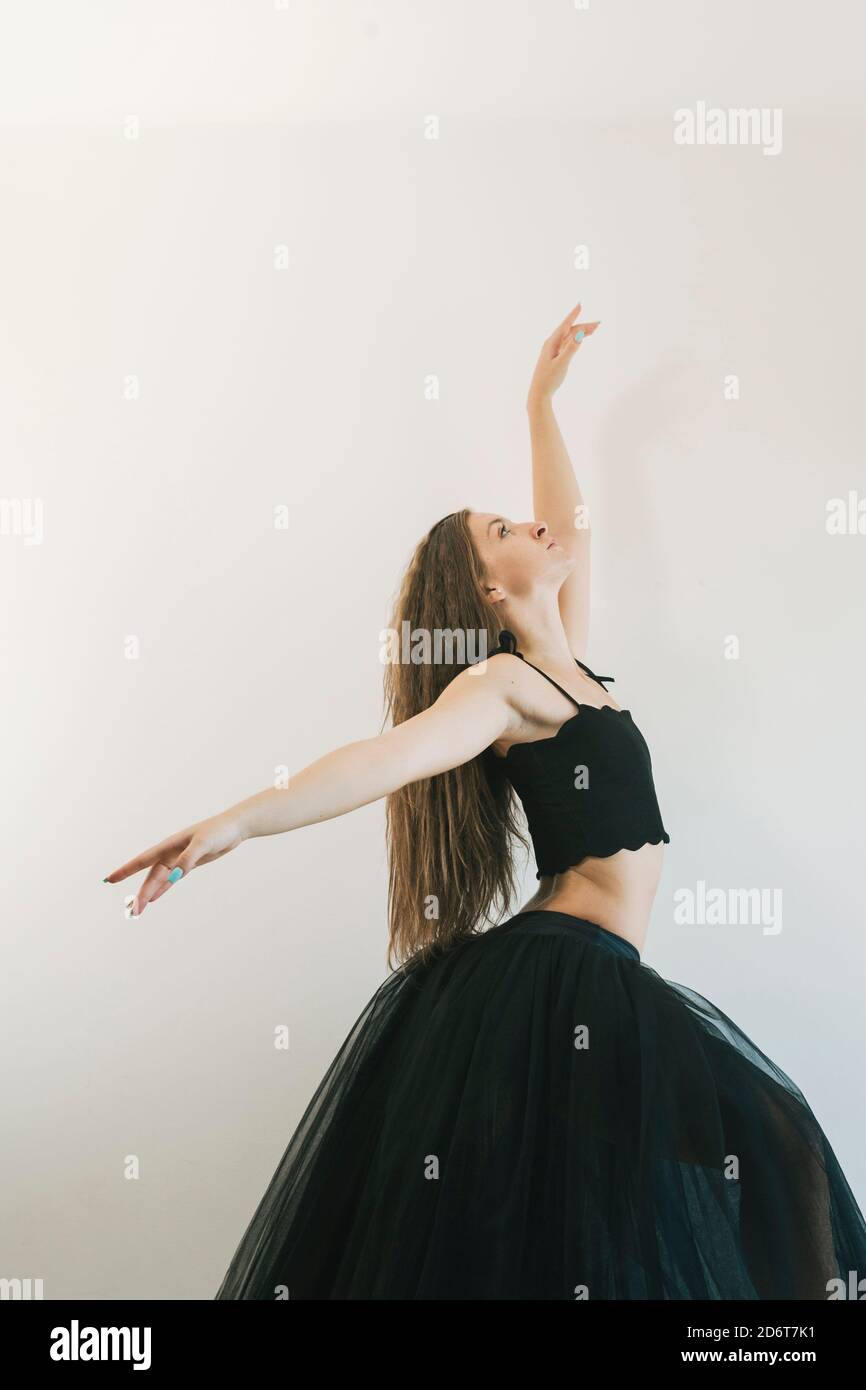 Side view of graceful female ballet dancer wearing black tutu standing ...