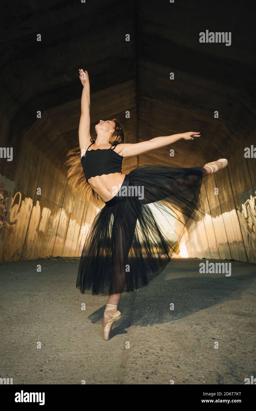 Elegant ballerina in black tutu and pointe shoes balancing on leg while ...