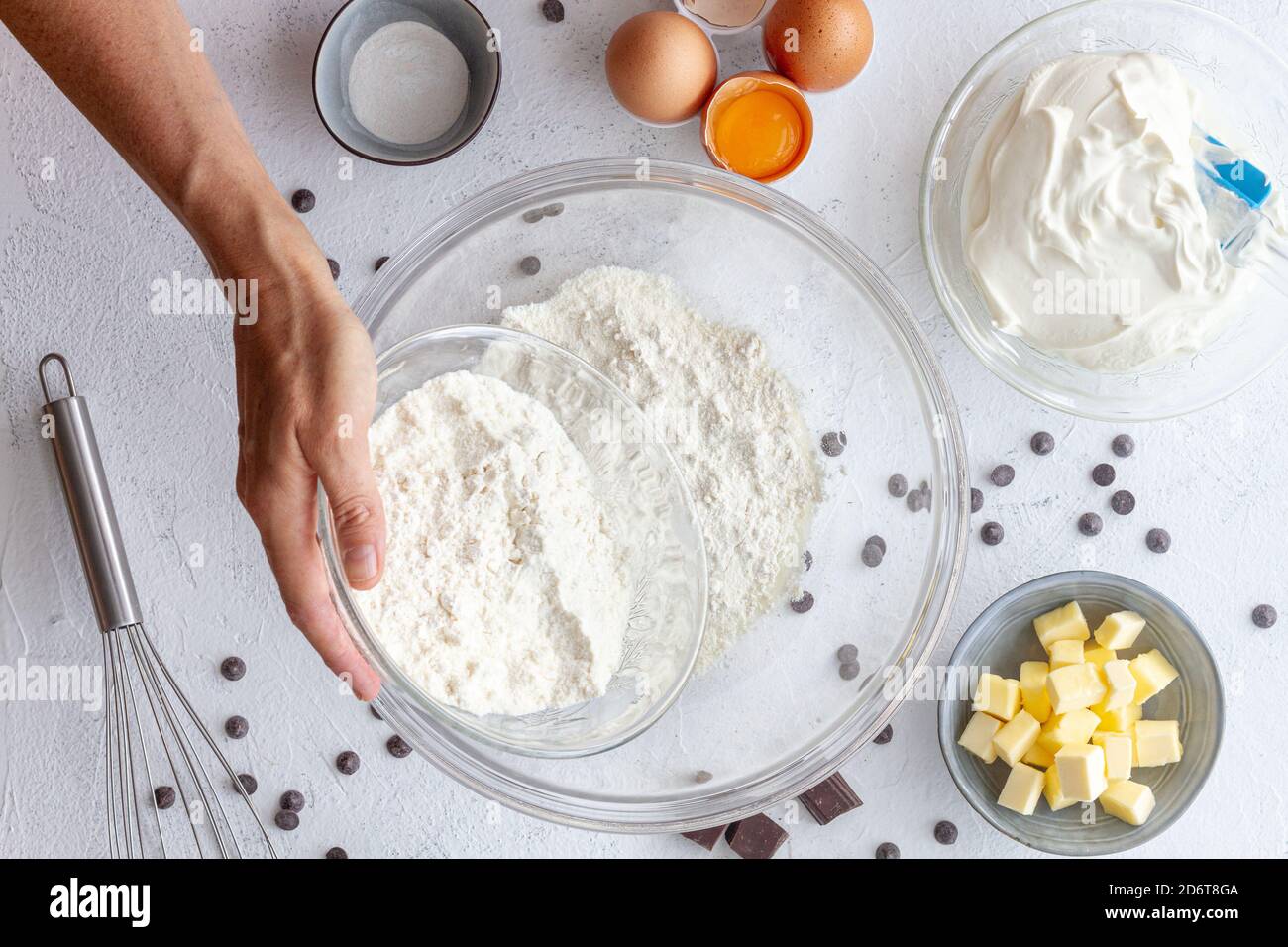 Top view crop faceless cook with whisk in hand above bowl with flour ...