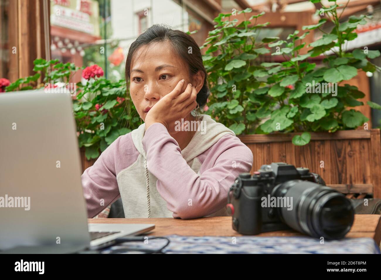 Concentrated Asian female journalist sitting at table with digital ...