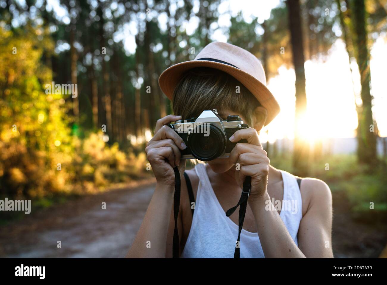 Unrecognizable female photographer in casual outfit and hat standing on ...