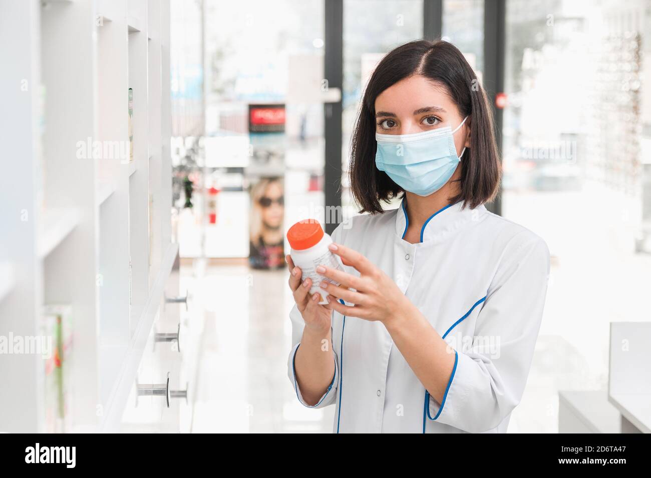 attractive ethnicity female pharmacist wearing medicine mask holding a ...