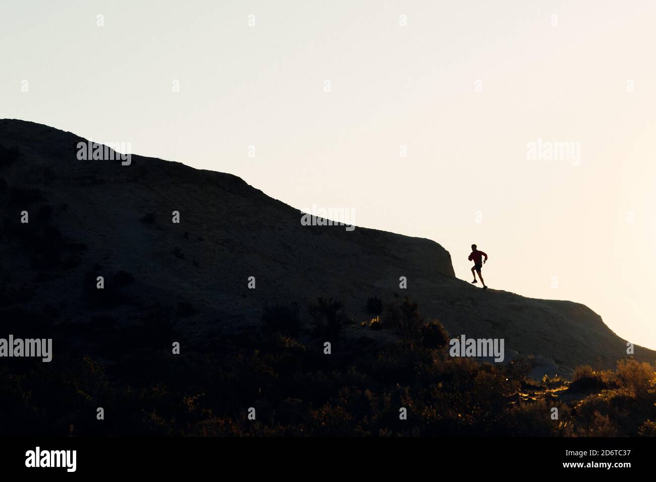 Side view silhouette of unrecognizable athlete running up on mountain ...