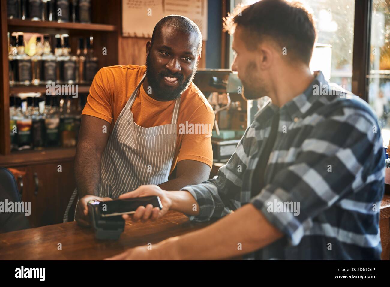 Cheerful bartender using terminal for contactless payment Stock Photo ...