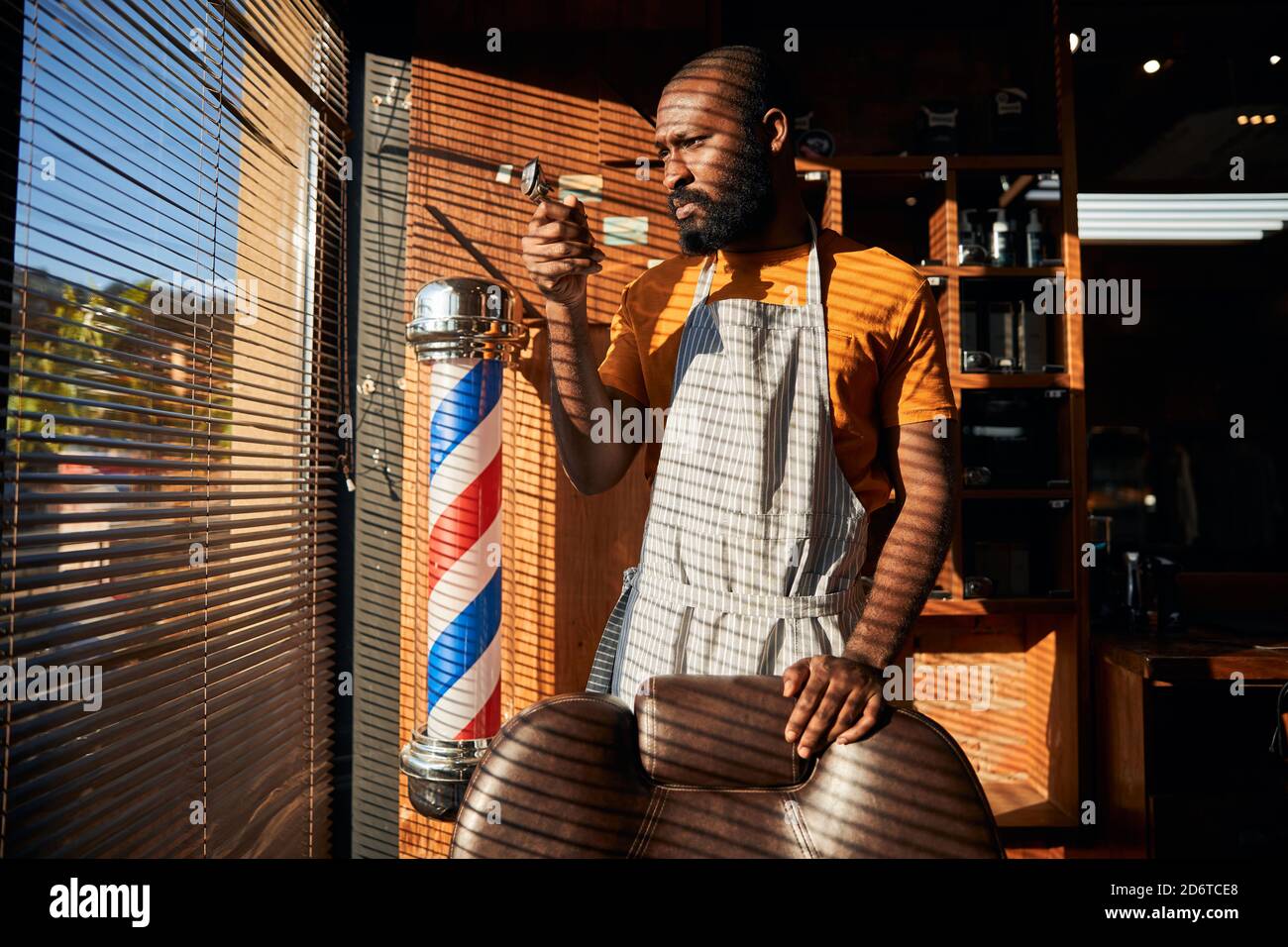 Handsome male barber in apron holding portable hair trimmer Stock Photo ...