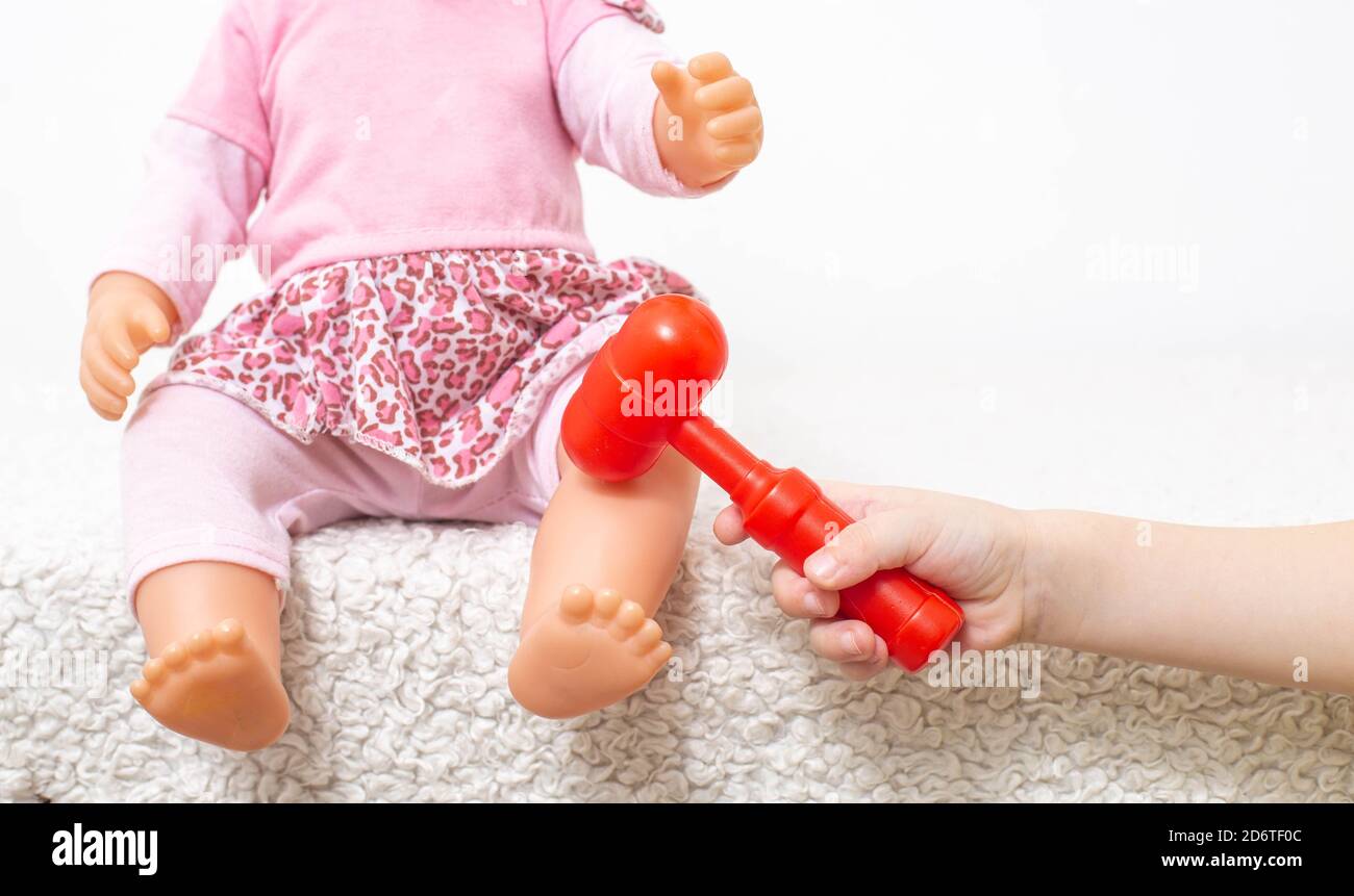 A little girl plays with a doll, and with a small neurological hammer ...