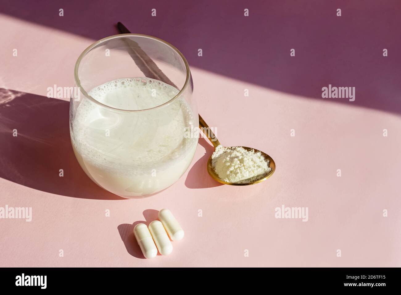 Collagen or protein powder in a glass on pink background. Natural ...