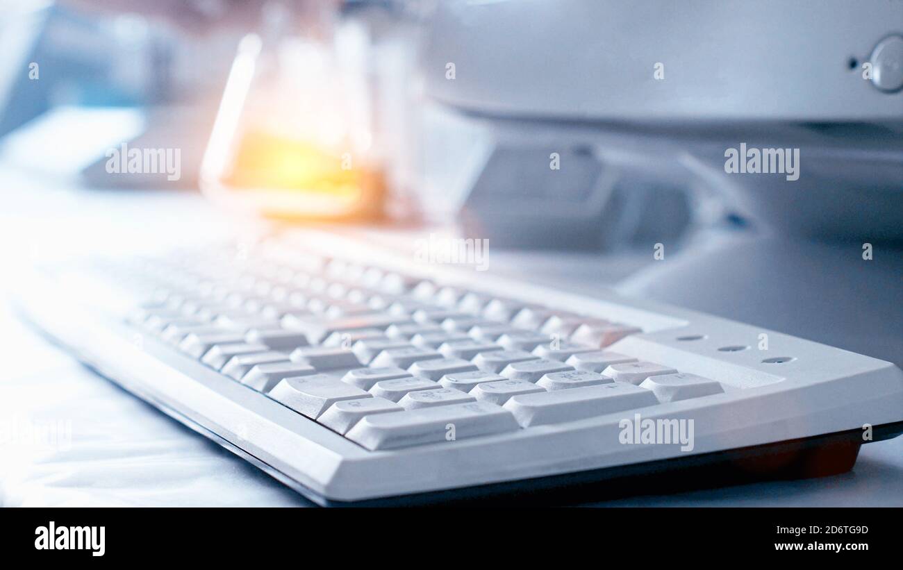 Computer keyboard and test tube with orange liquid in the laboratory ...