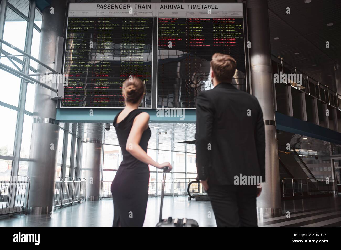 Man and woman looking a the timetable a the station Stock Photo - Alamy