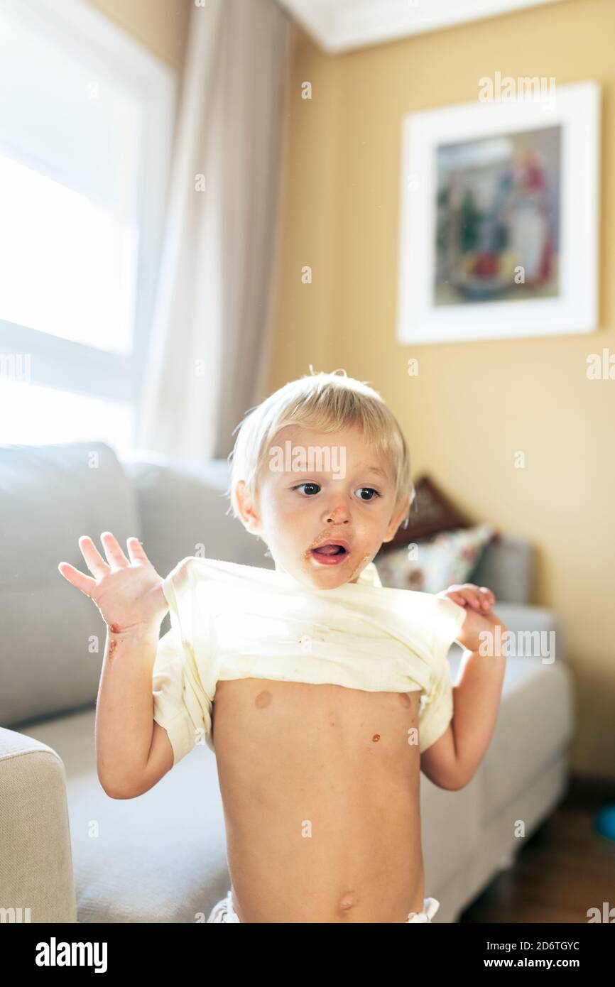 Funny little boy lifting t shirt up while playing in living room at ...