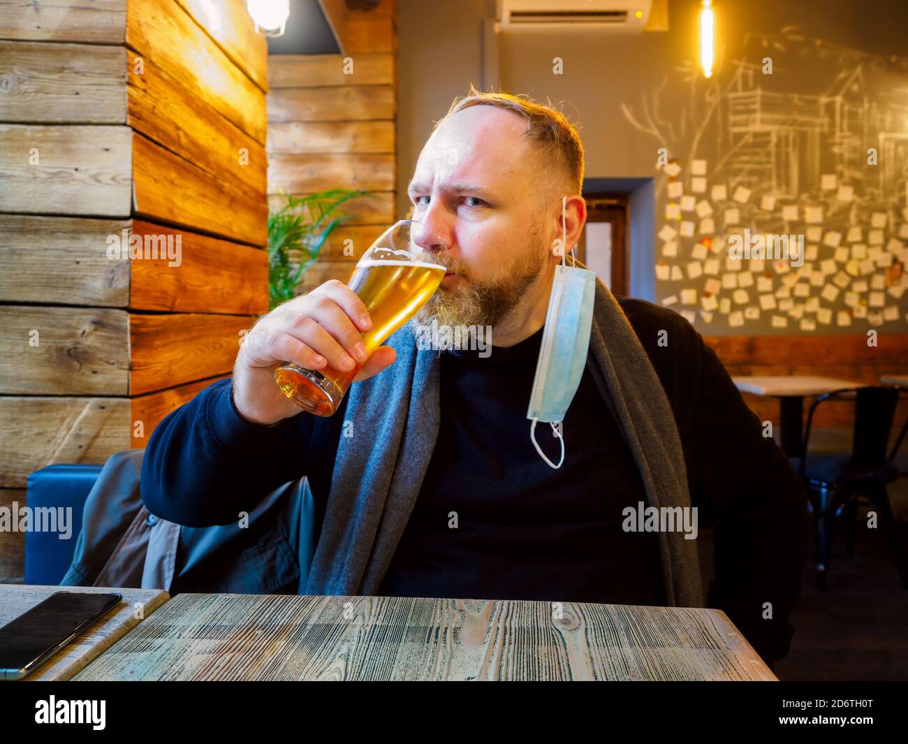 adult european man wearing a mask try to drink a beer in a pub Stock ...