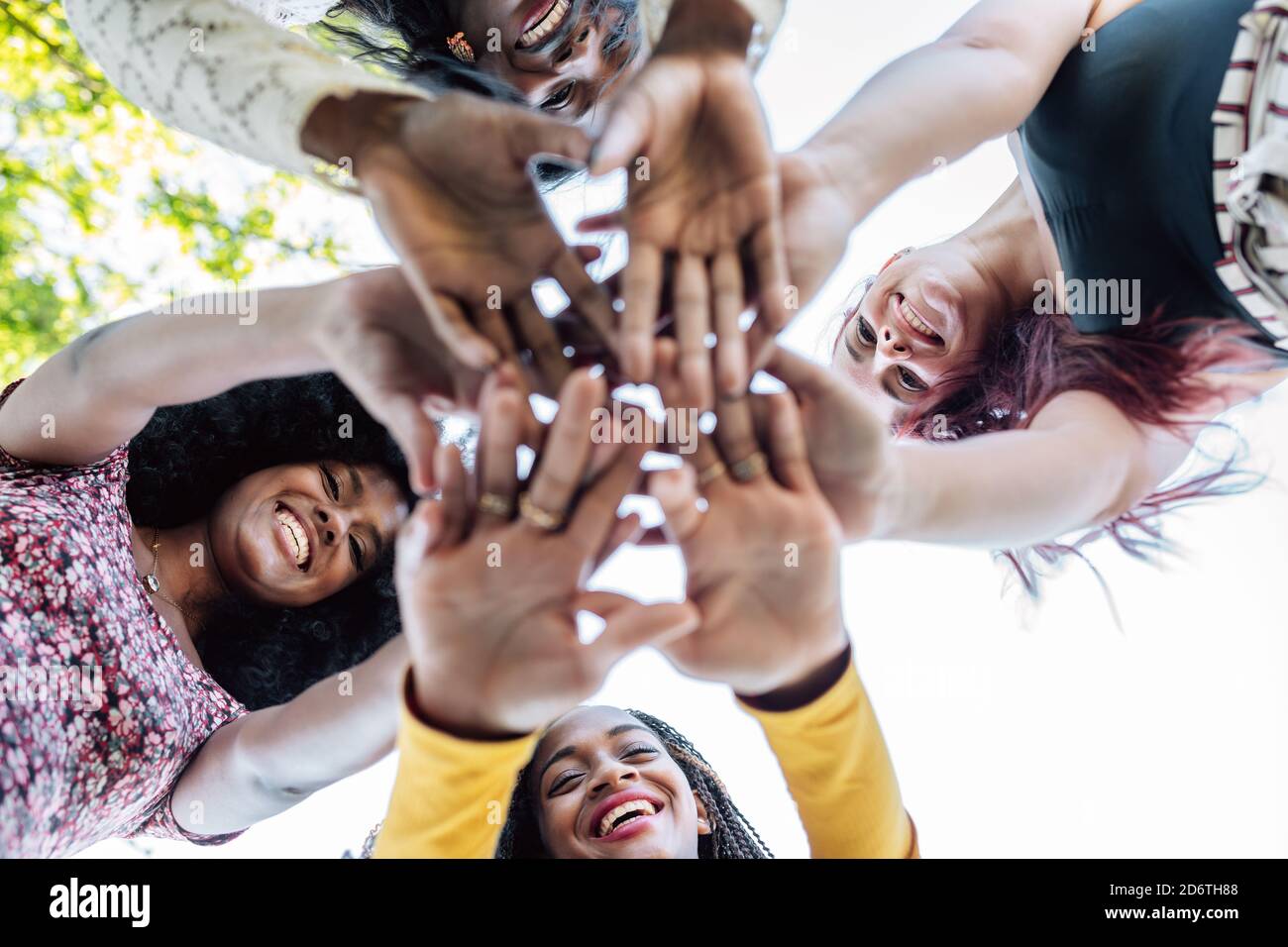 From below of group of multiracial cheerful women standing together and ...