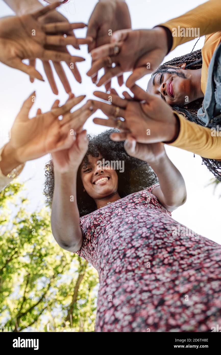 From below of group of multiracial cheerful women standing together and ...