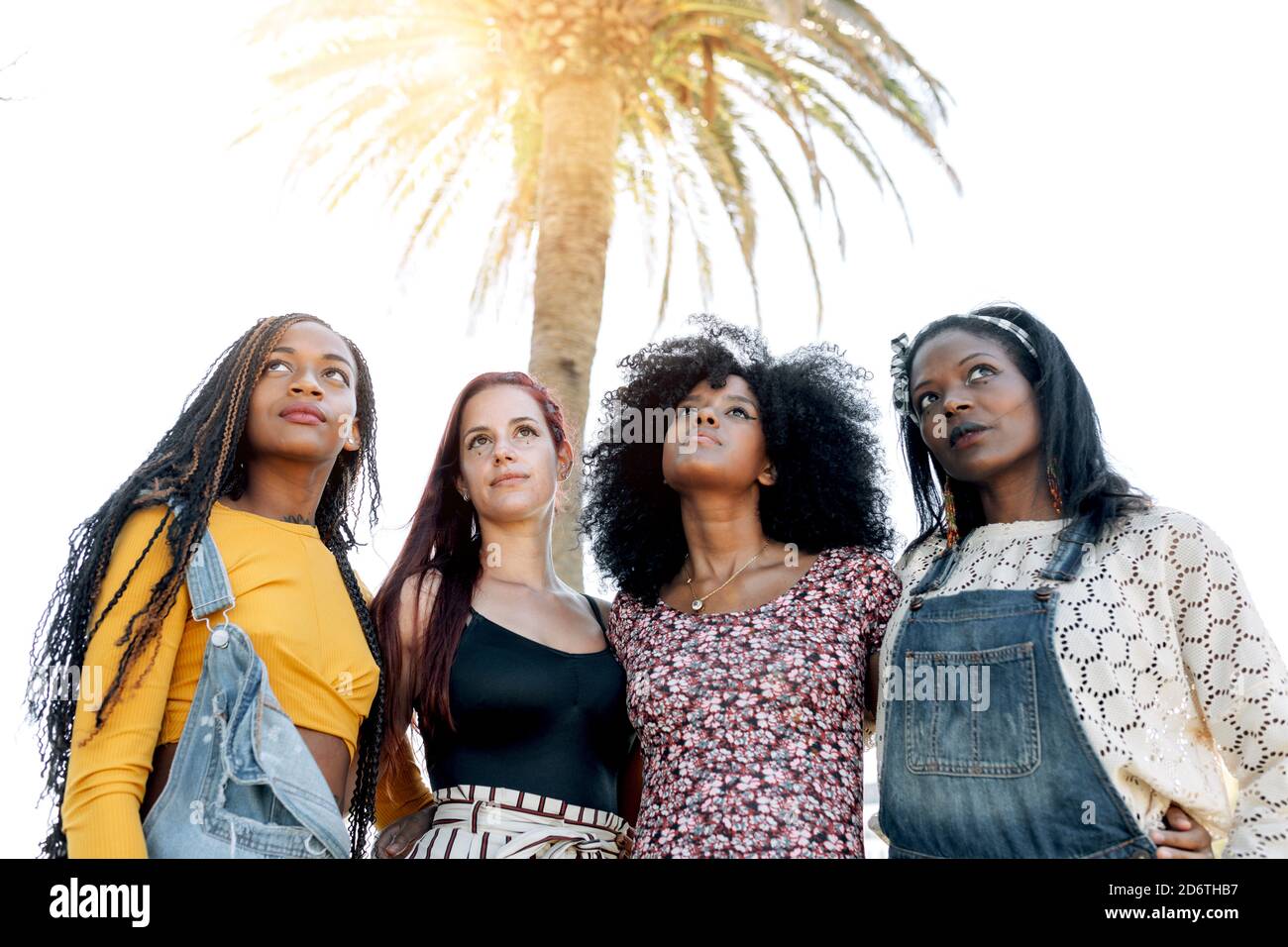Friendly multiracial group of female friends cuddling on street while ...