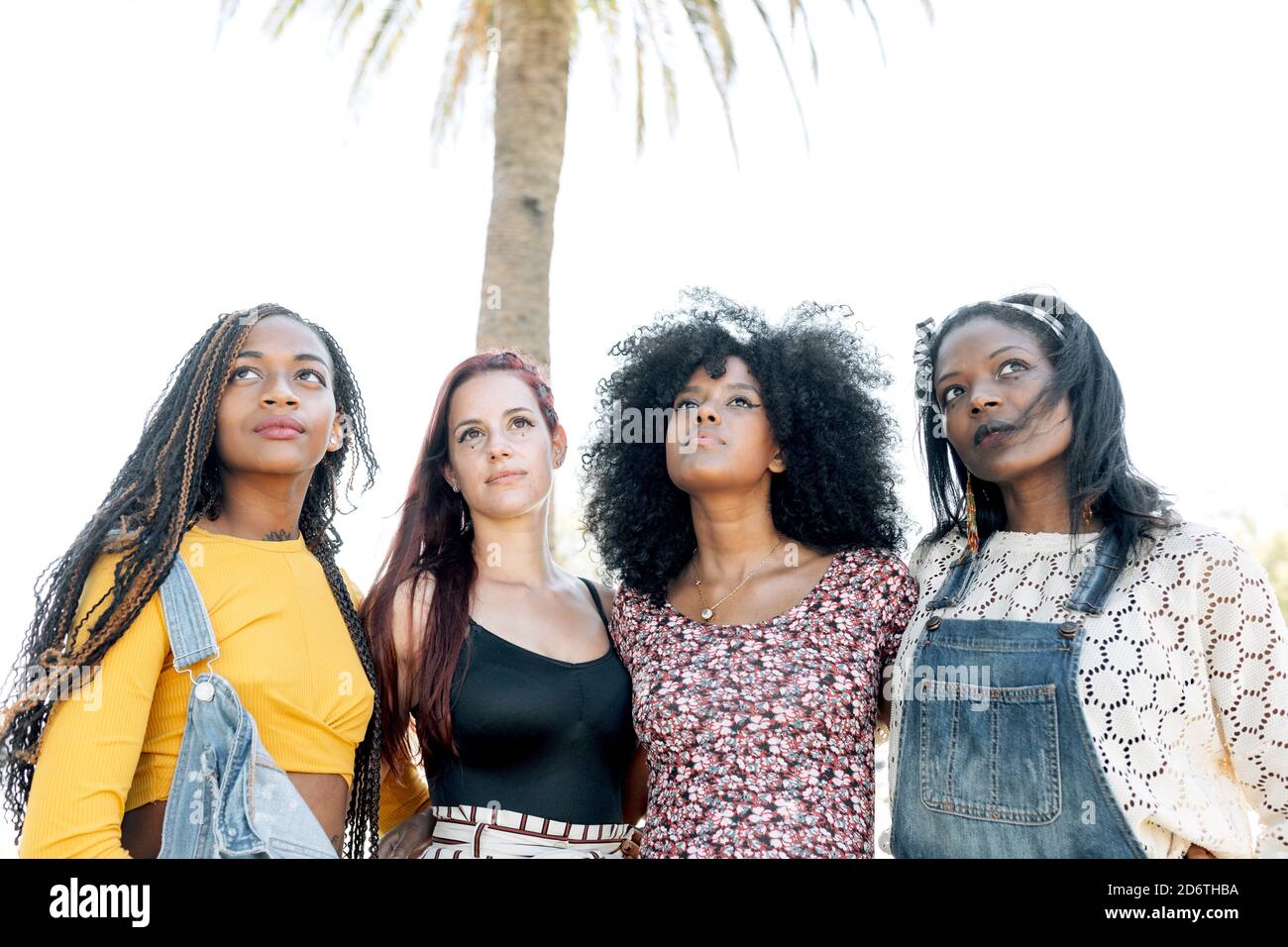 Friendly multiracial group of female friends cuddling on street while ...