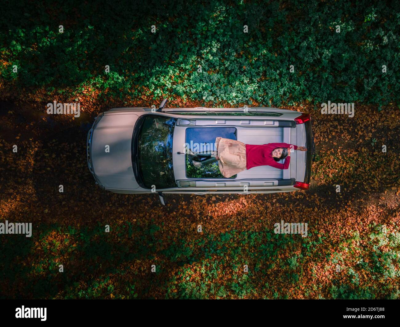 aerial view woman laying down on suv car roof in the middle of the ...