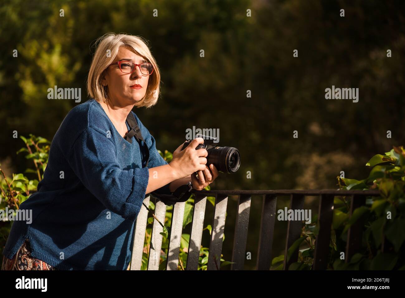 Side view of serious adult blond female photographer with professional ...