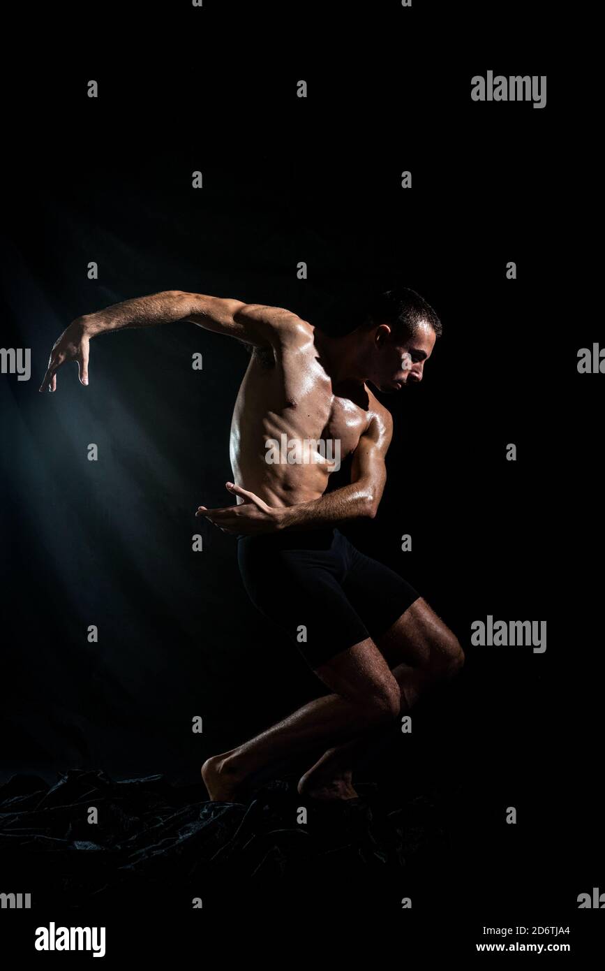 Full body of faceless tanned sporty shirtless dancer in shorts raising ...