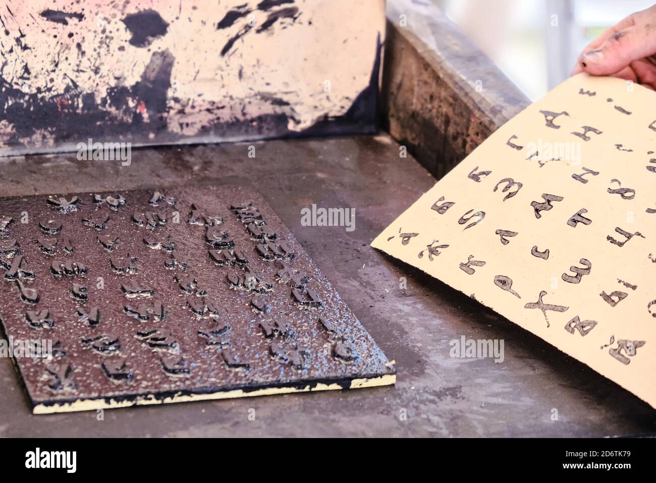 A man takes a printed sheet of paper. Cyrillic alphabet for printing in ...