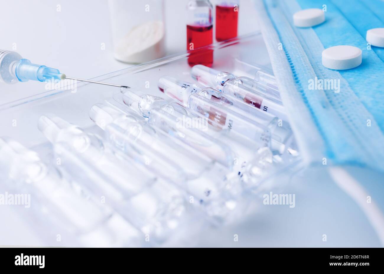 Syringe and a row of vials of medicine on a white table. Horizontal ...