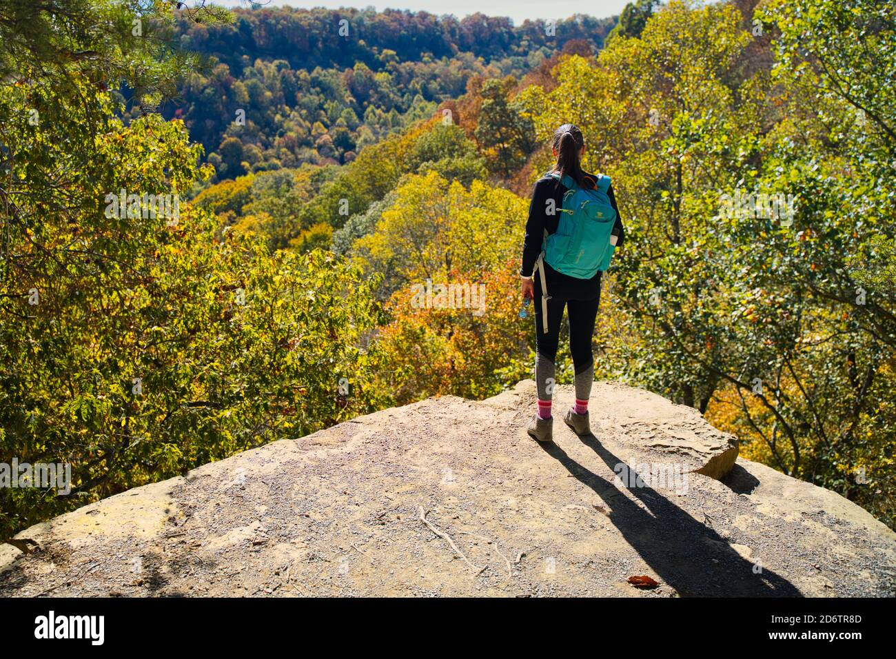 Lady standing on edge of cliff with colorful fall colors in background ...
