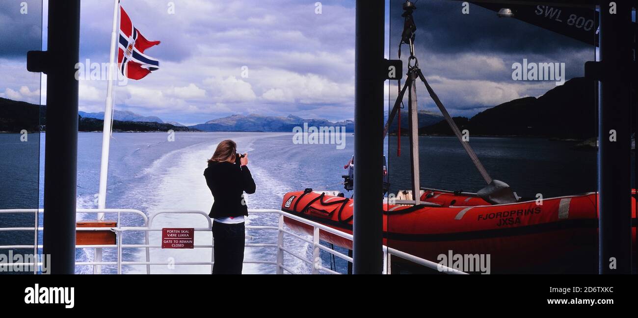 A tourist taking a photograph of the picturesque Fjaerland Fjord viewed ...