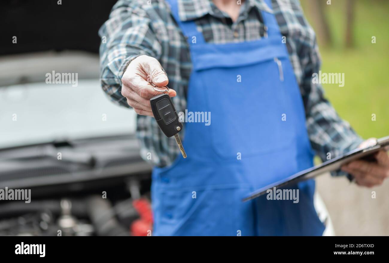 Car mechanic delivering car keys after car engine checking Stock Photo ...