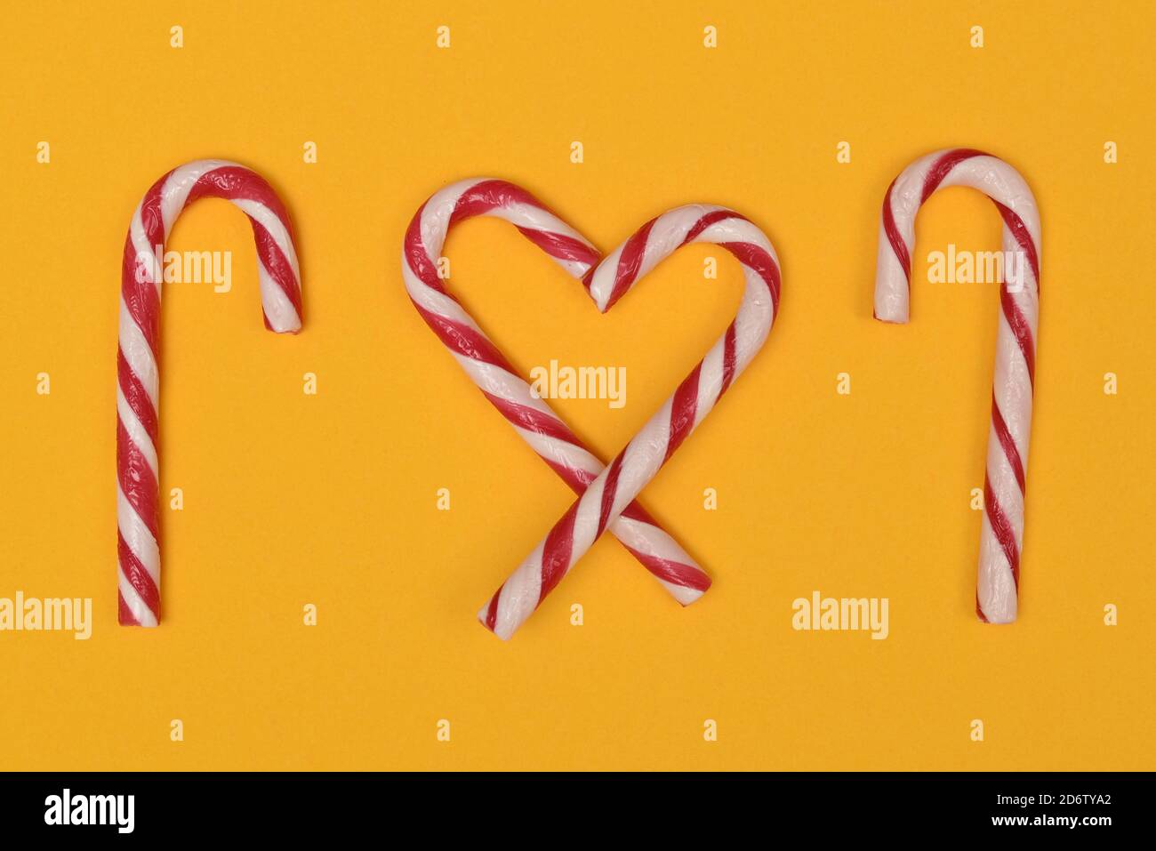 Candy cane heart and canes on a yellow background Stock Photo - Alamy
