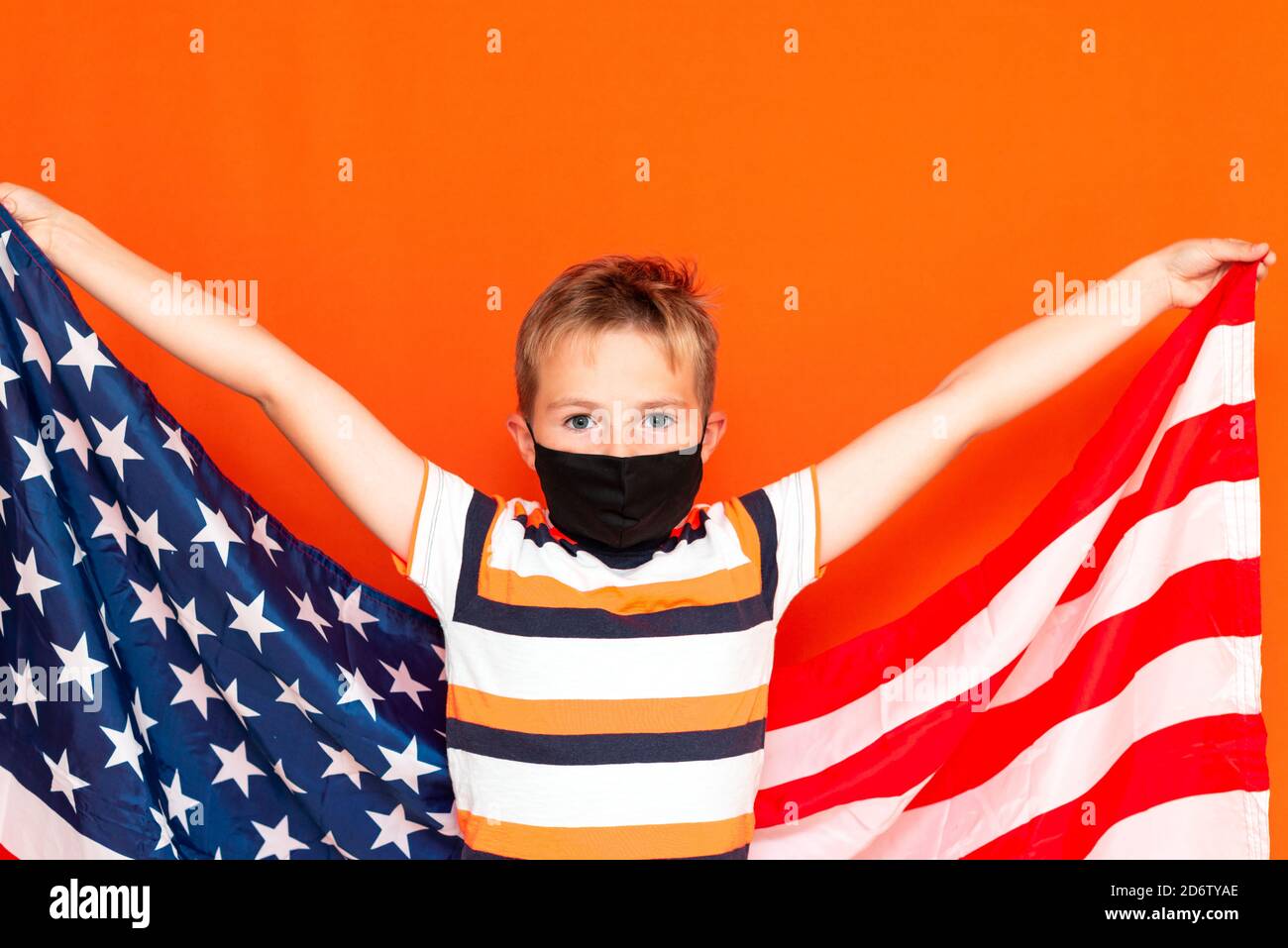 Portrait of a young boy wearing black face mask holding american flag ...