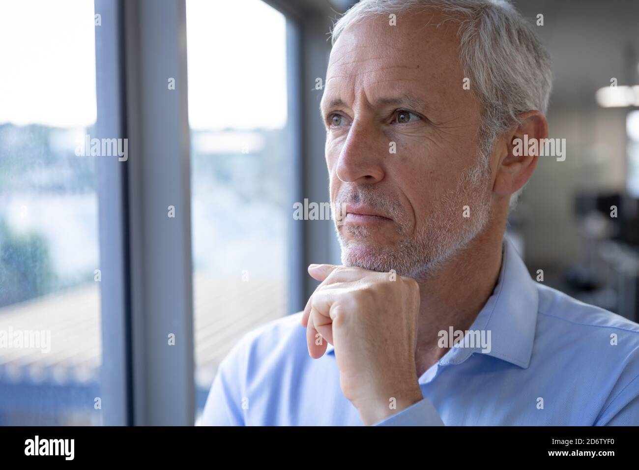Senior businessman with hand on his chin looking through window at ...