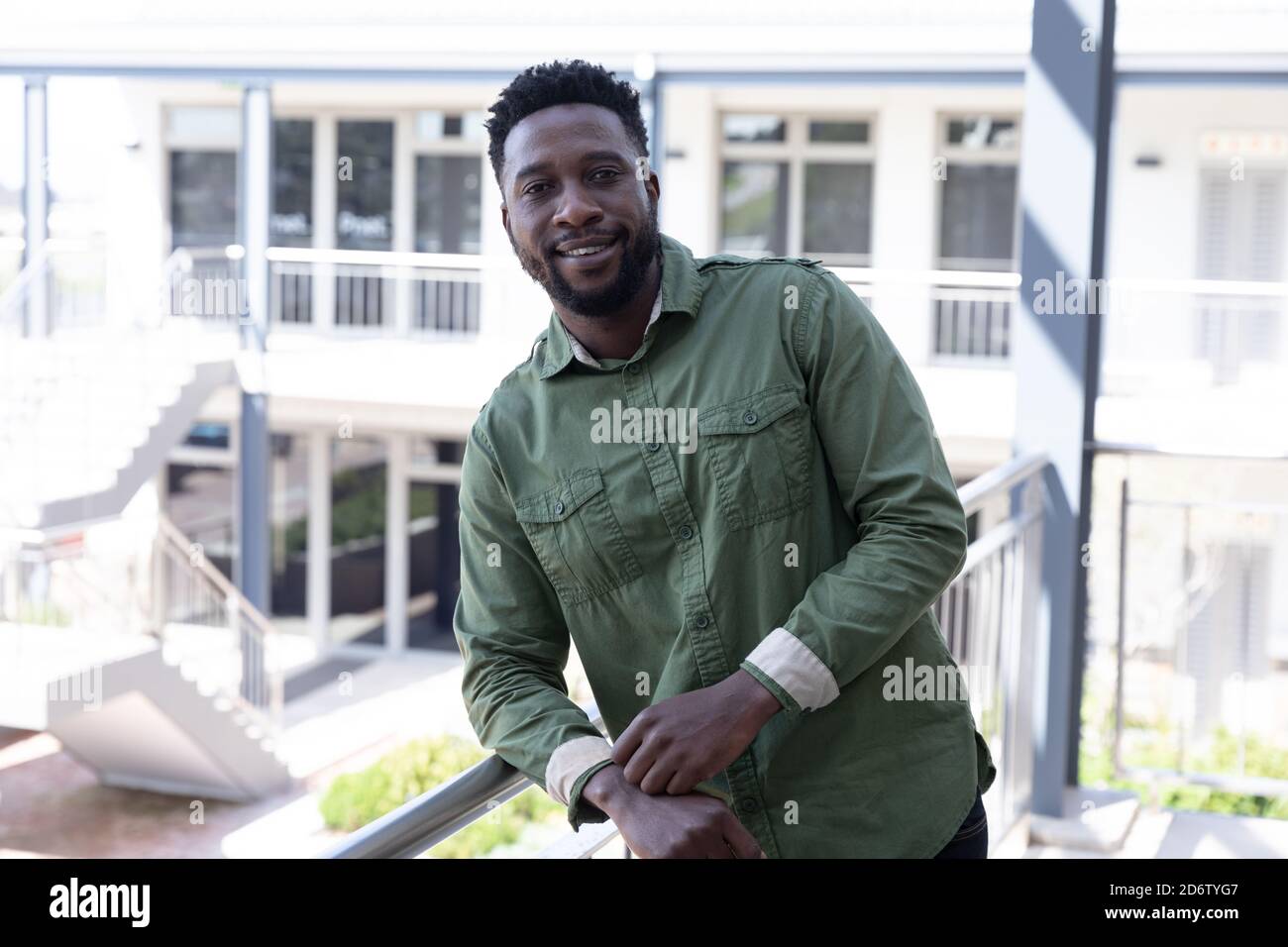 Portrait of Businessman leaning on railing in balcony at modern office ...