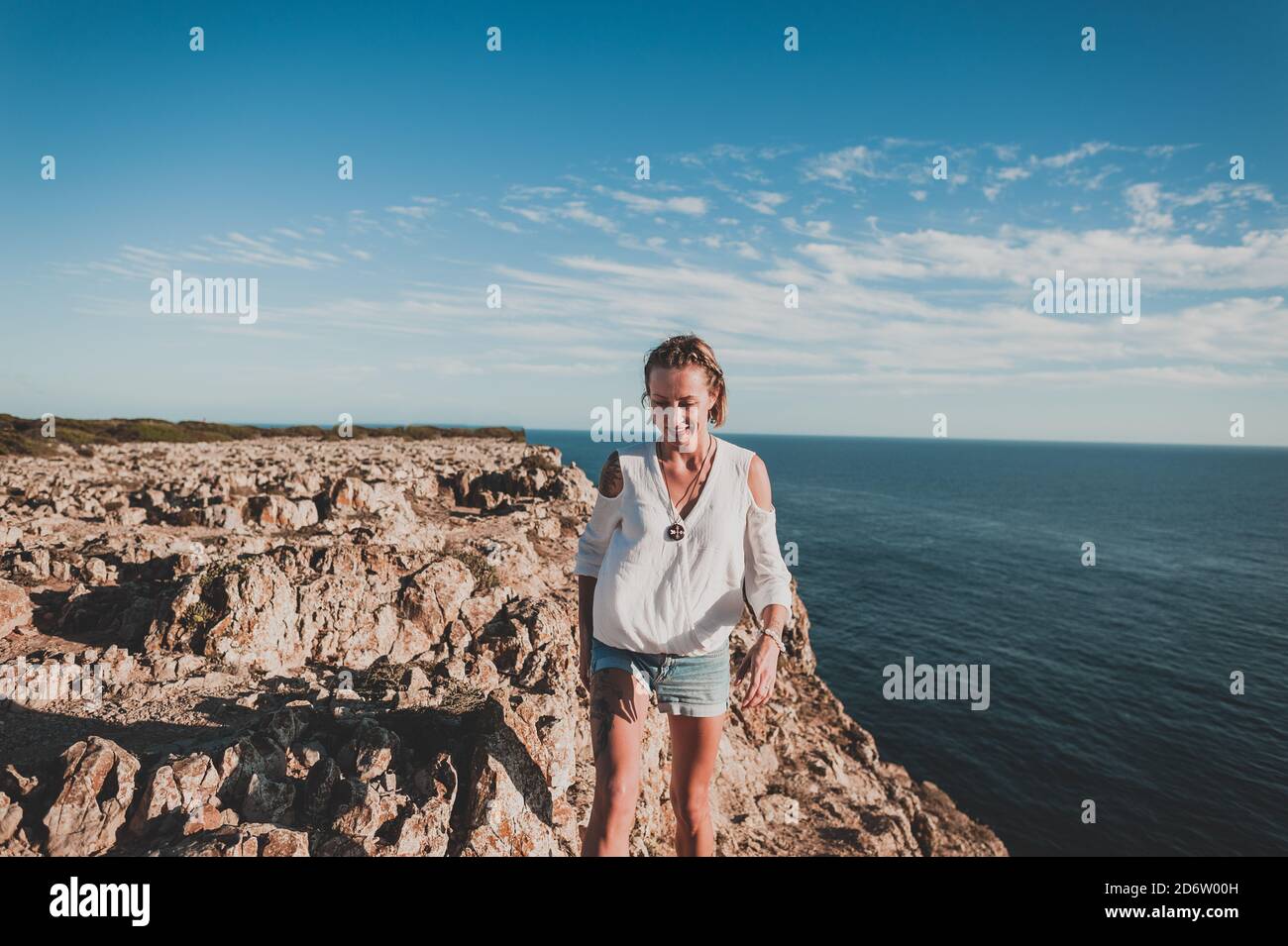 Young woman on cliff looking out over ocean in summer in Portugal Stock ...
